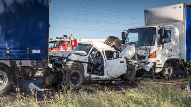 Car wedged between two trucks in Truganina