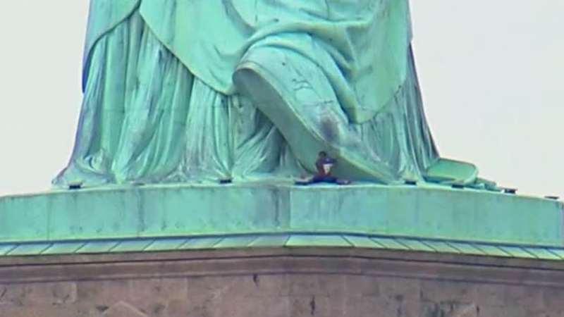 Climber sits at Statue of Liberty's feet