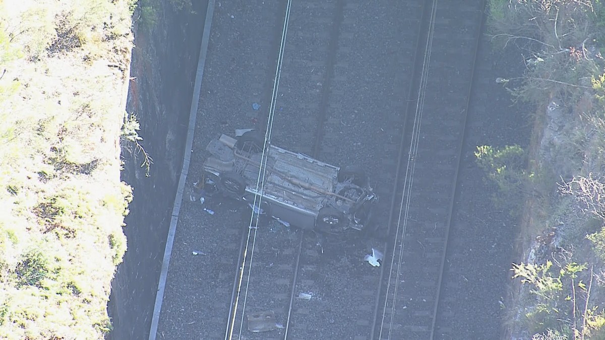 Car crashes upside down onto train tracks west of Sydney | Nine.com.au